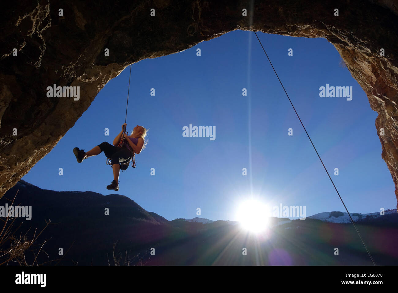 Female rock climber hanging on rope above cave at sunset hi-res stock ...