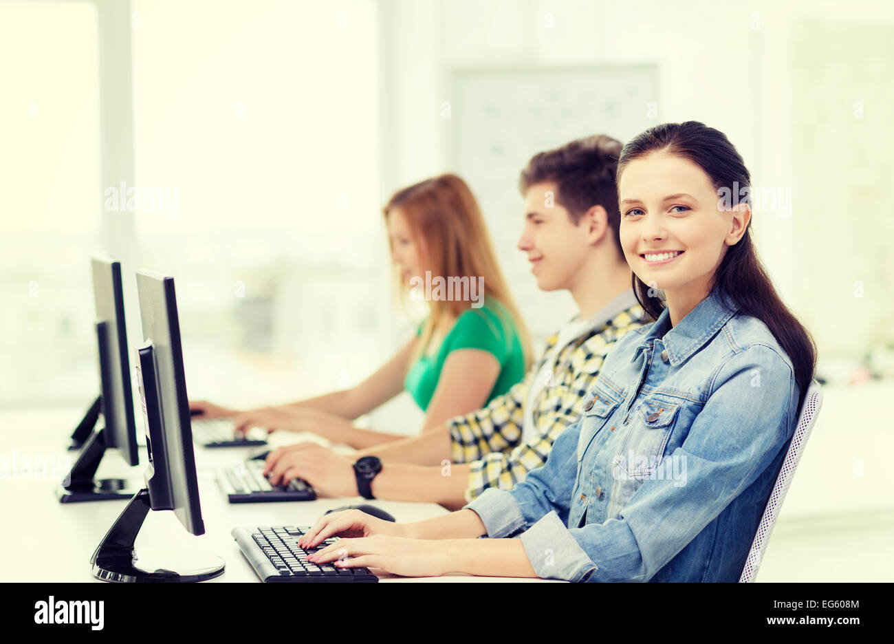 three smiling students in computer class Stock Photo - Alamy