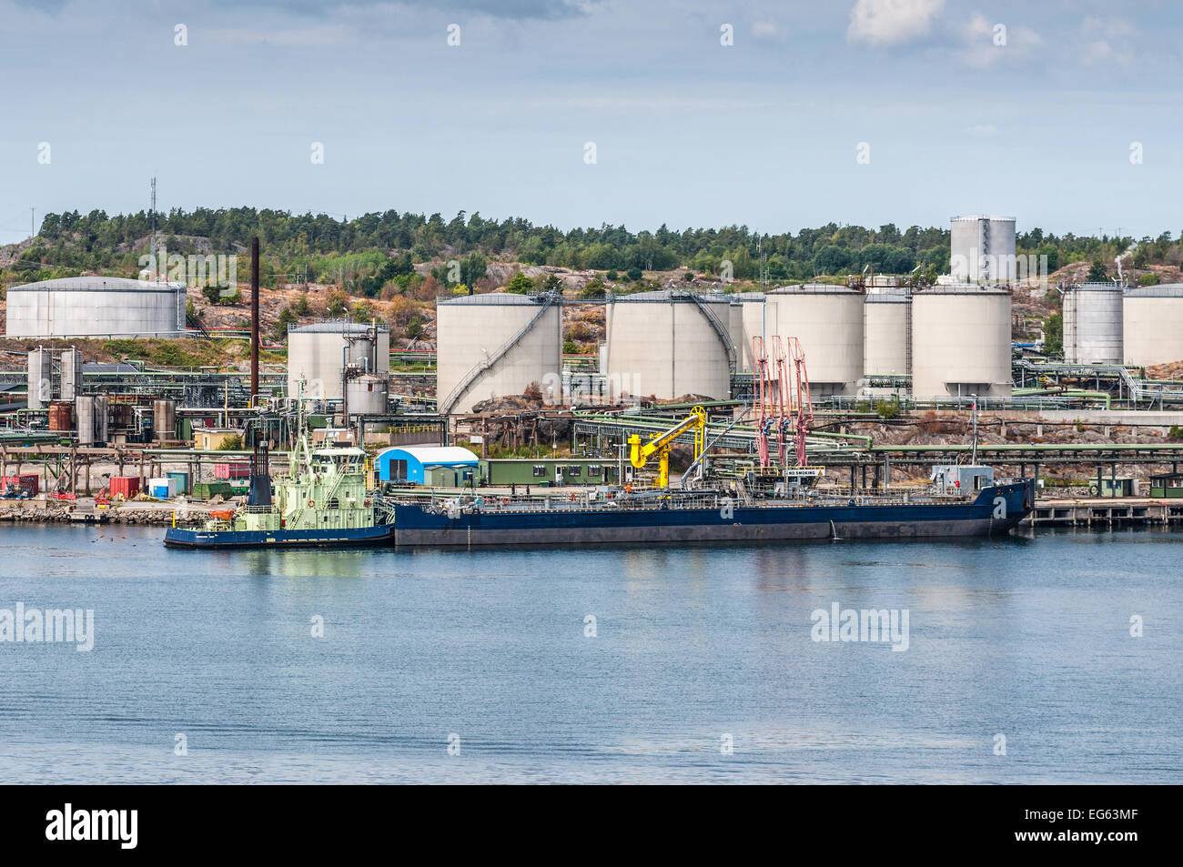 Tanker unloading with oil storage tanks in the background Stock Photo ...