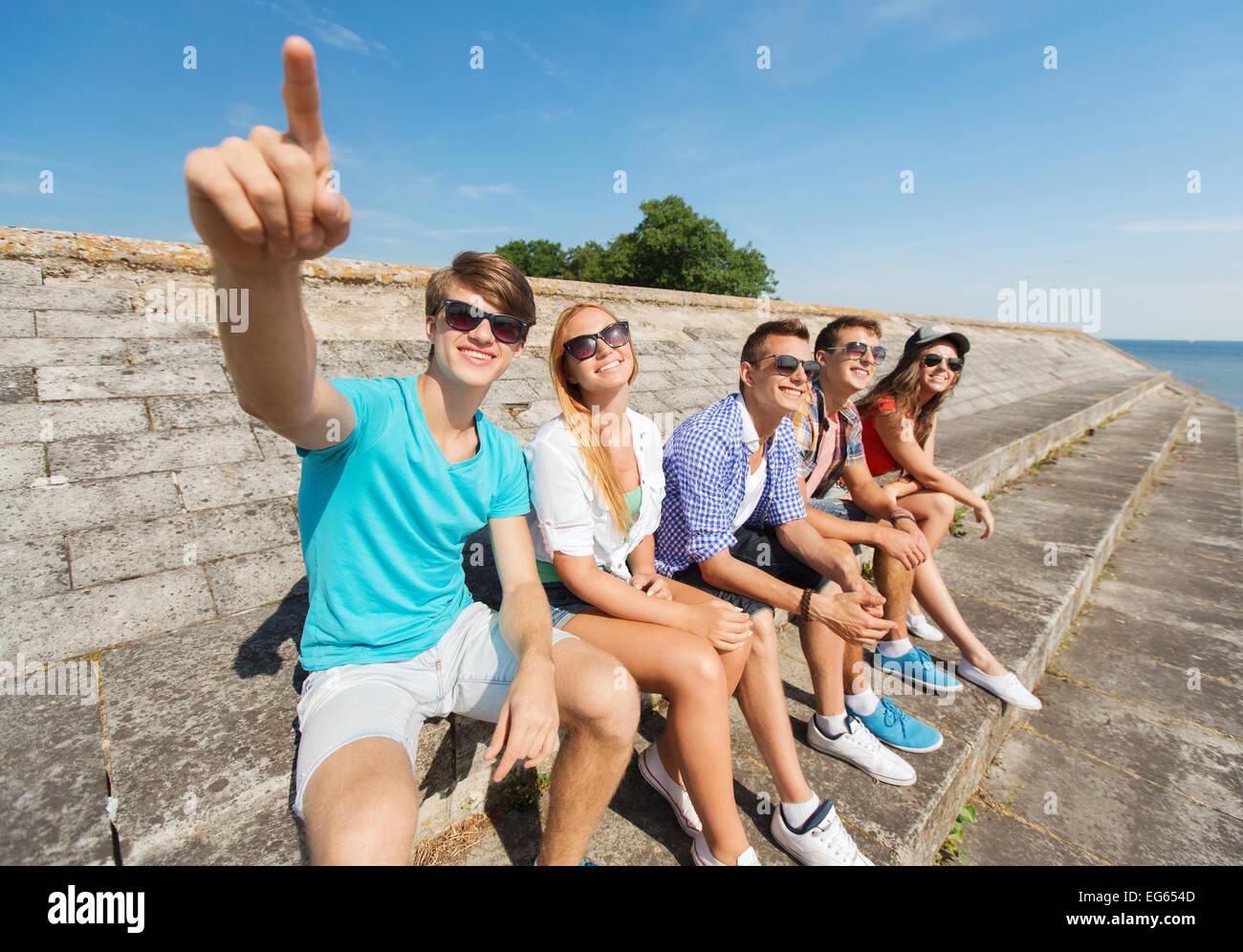 group of smiling friends sitting on city street Stock Photo - Alamy