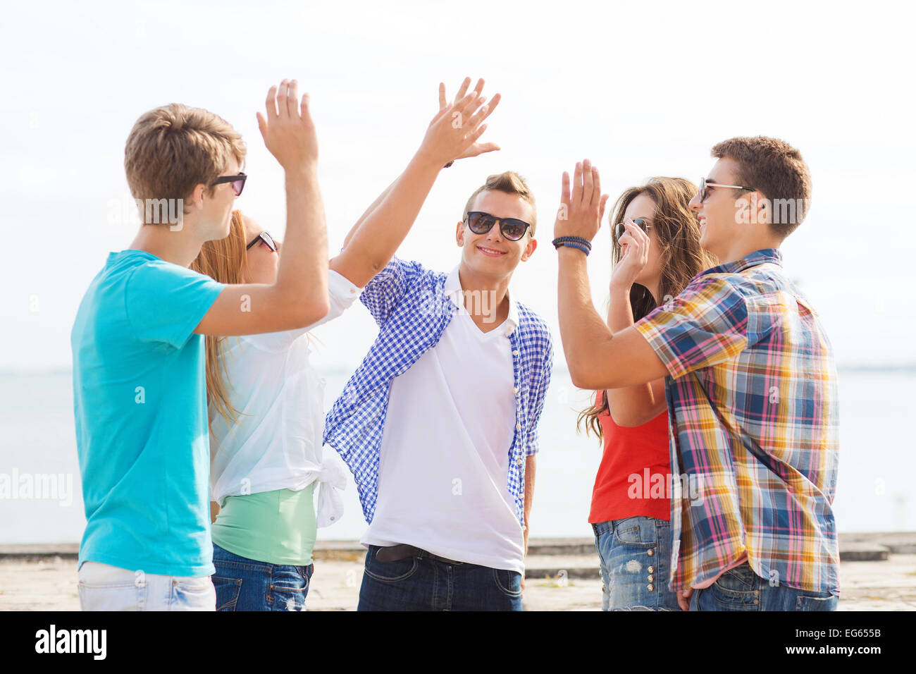 group of smiling friends making high five outdoors Stock Photo - Alamy