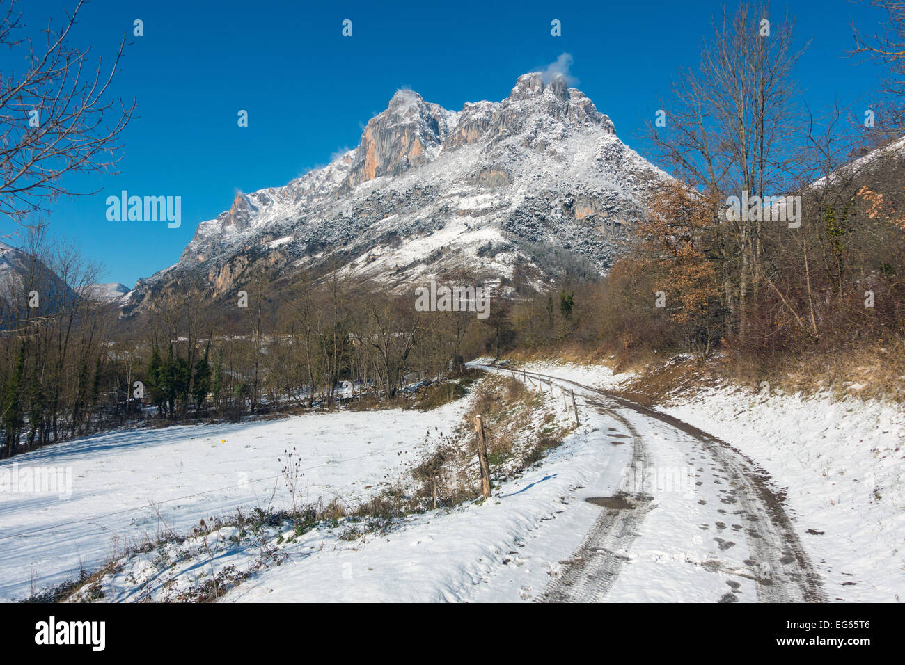 Snowy track with tire marks leading toward snow covered mountain ...