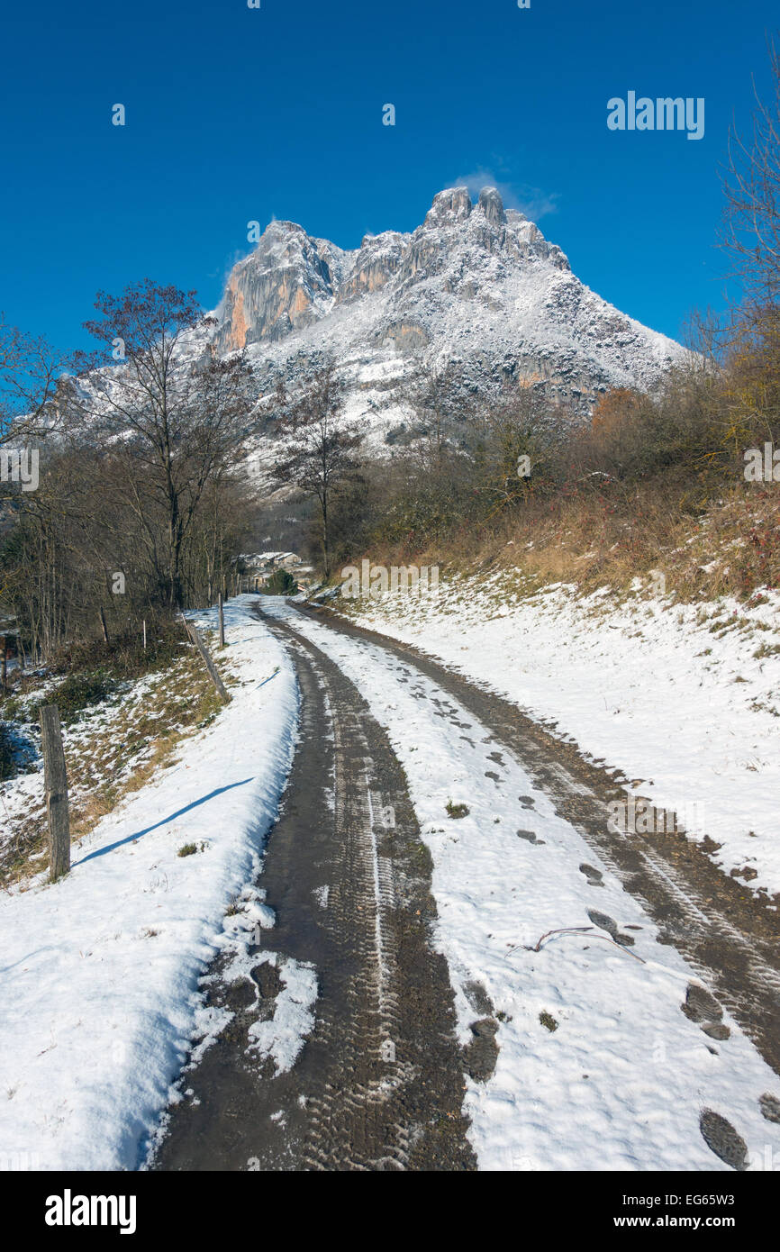 Snowy track with tire marks leading toward snow covered mountain ...