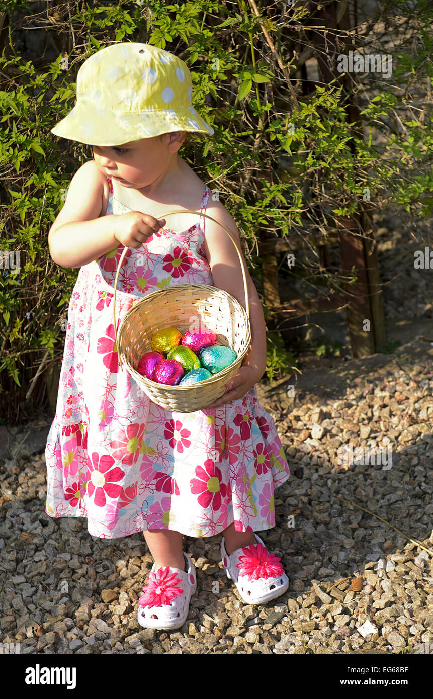 Girl toddler on Easter egg hunt with basket for eggs, release may be ...