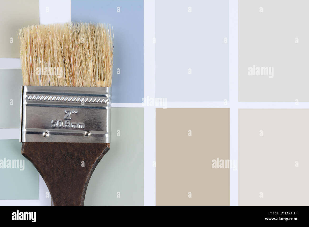 Overhead shot of a paint brush with a brown handle laying on a sheet of ...