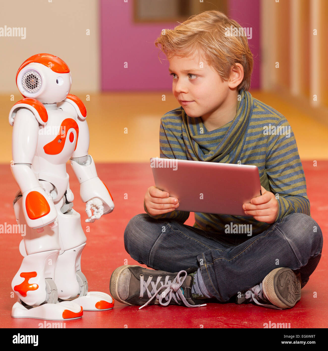 Young child playing with humanoid robot during school time Stock Photo ...