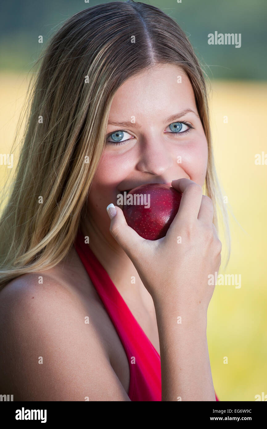 Beautiful smiling young woman and bit red apple, against background of ...