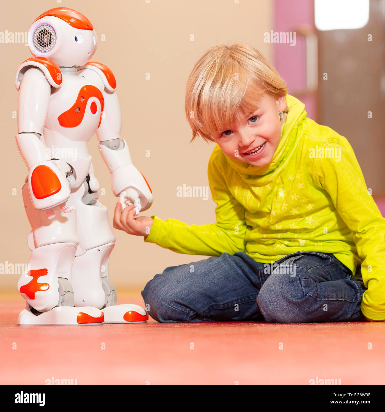 Young child playing with humanoid robot during school time Stock Photo ...