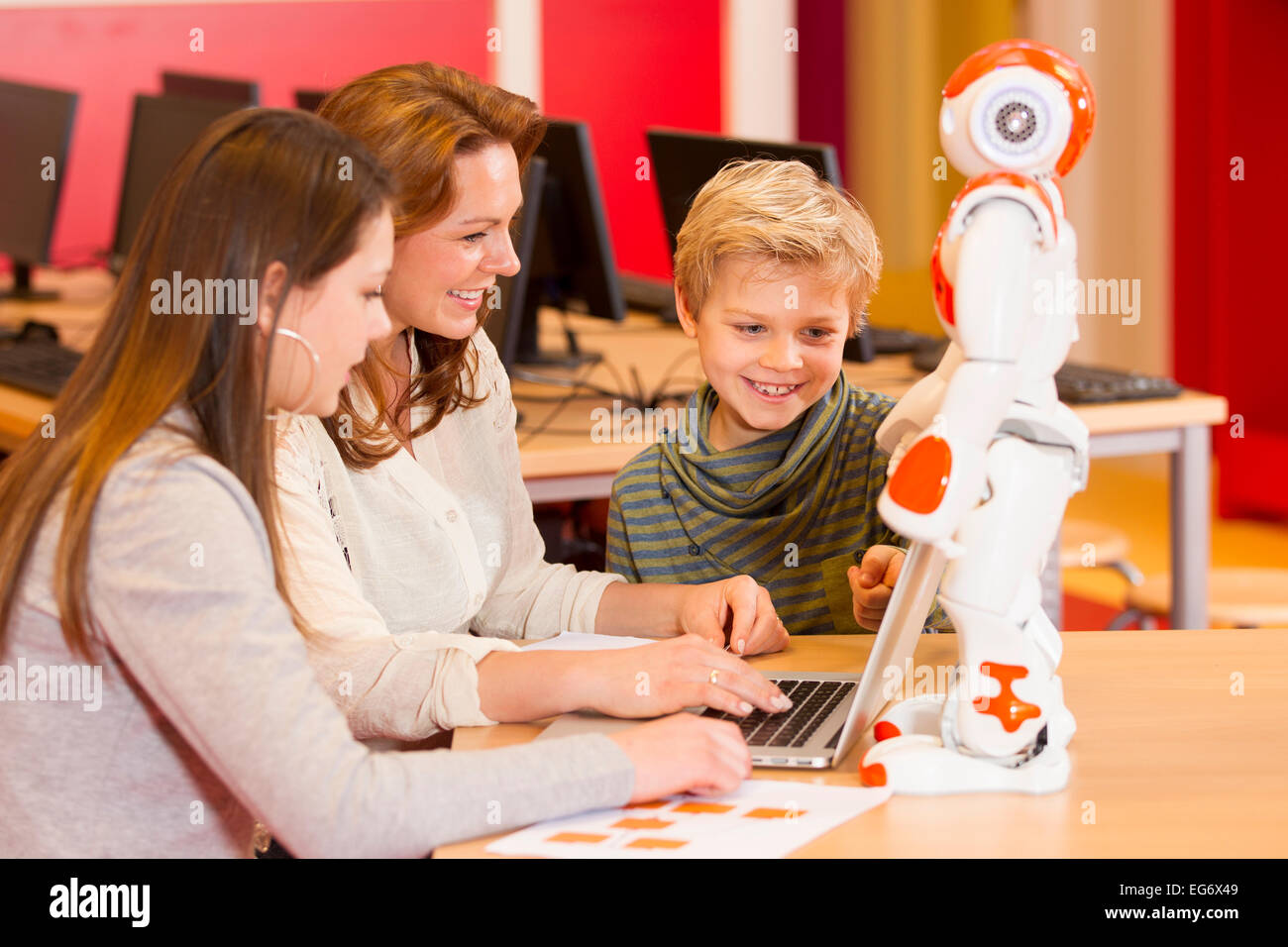 Two children programming a robot with their science teacher on a ...