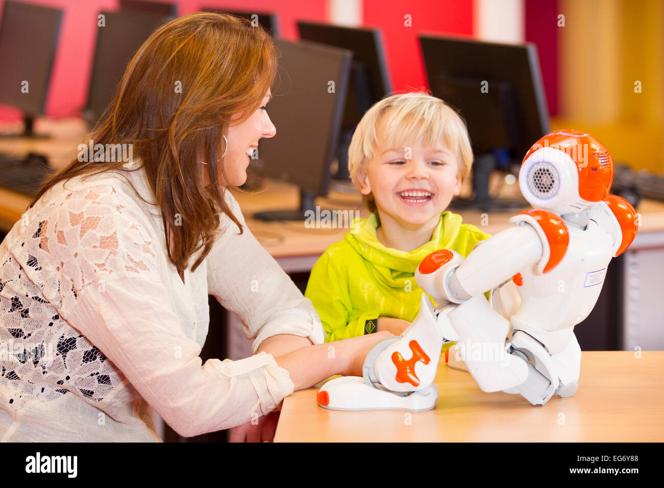 One young boy programming a robot with his science teacher on a primary ...