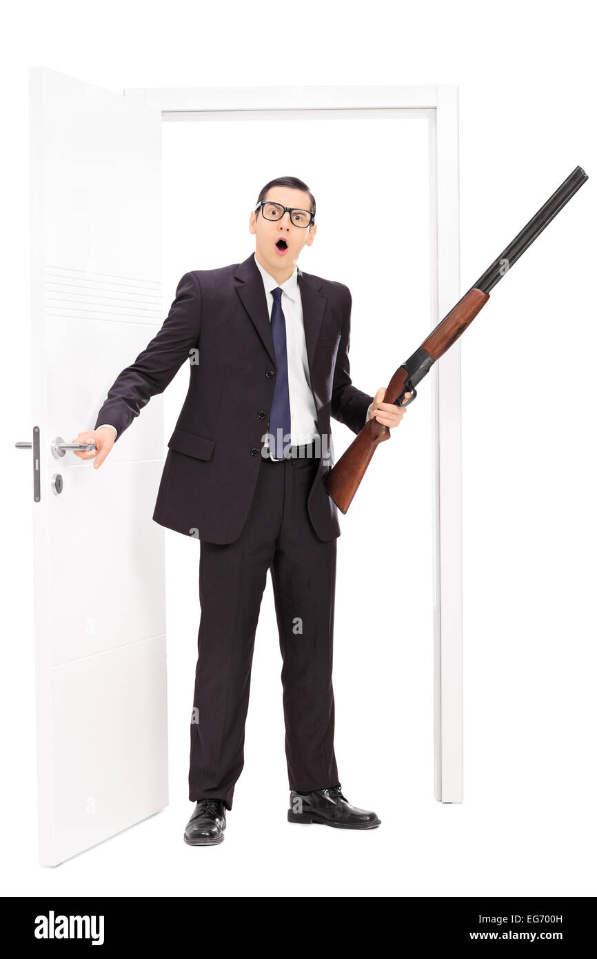 Full length portrait of a man with rifle standing by a door isolated on ...