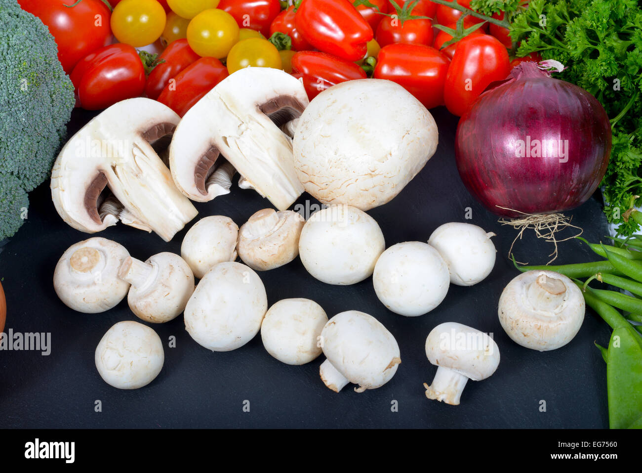 Paris mushrooms on a slate plate with tomatoes and oinons Stock Photo ...