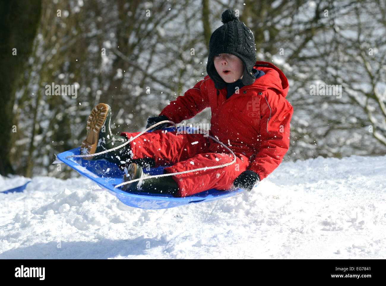 A young boy flies through the air on his sledge as he enjoys the ...