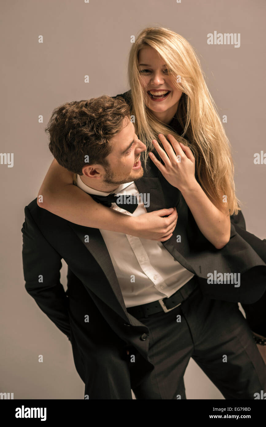 Man wearing tuxedo giving laughing blond woman a piggyback Stock Photo ...