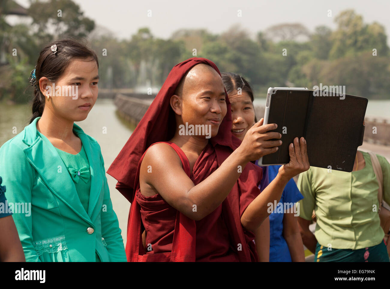 A buddhist monk showing people photos on his tablet computer, Yangon ...