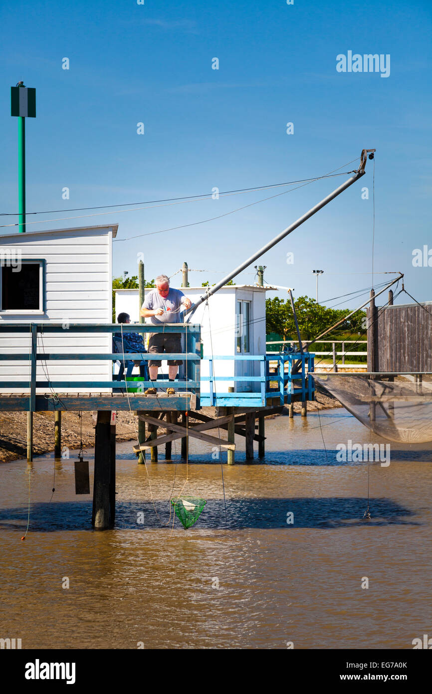 Man raising net on Traditional fisherman huts on stilts with carrelets ...