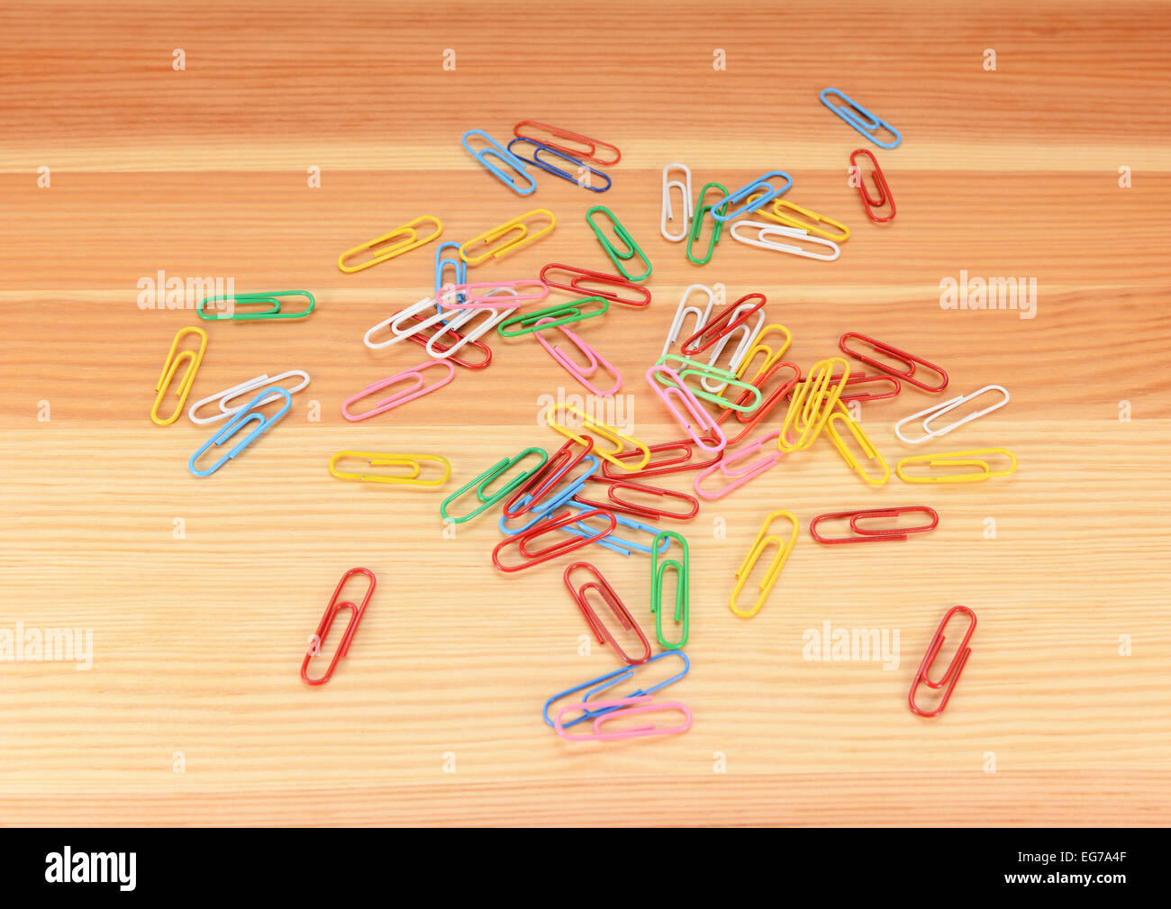 Multi-coloured paper clips scattered across a wooden background Stock ...
