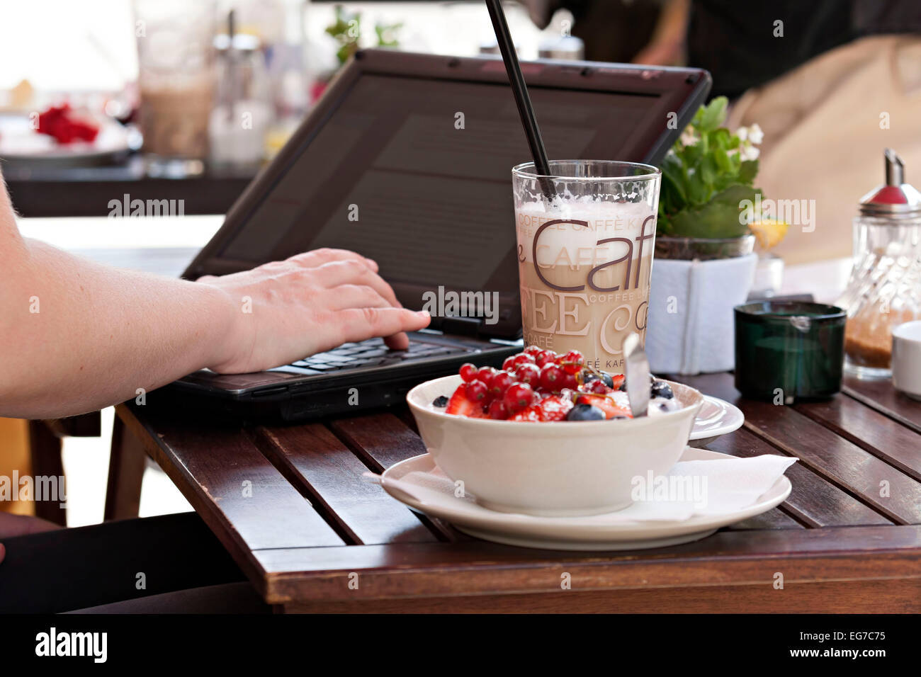 Person using laptop at a outside restaurant table Stock Photo - Alamy