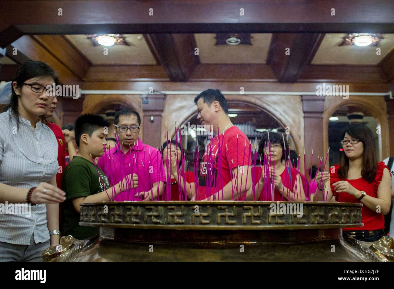 Family members put their incense in a golden pot located at the center ...