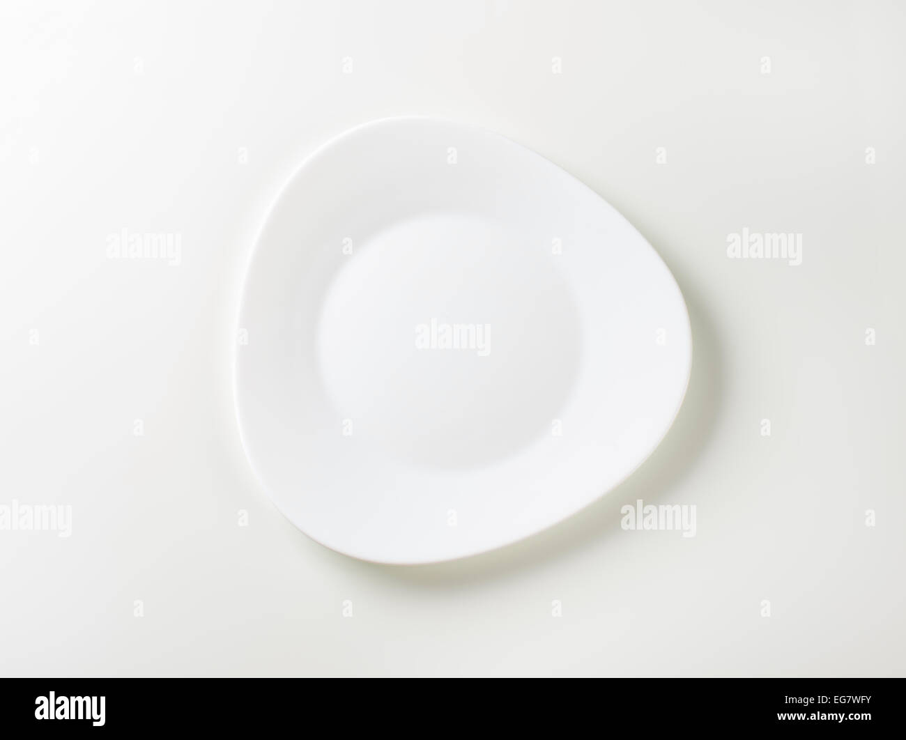 Triangle white plate with rounded edges and wide rim Stock Photo - Alamy