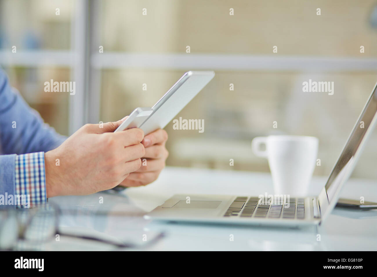 Male hands holding cellphone and touchpad with laptop near by Stock ...