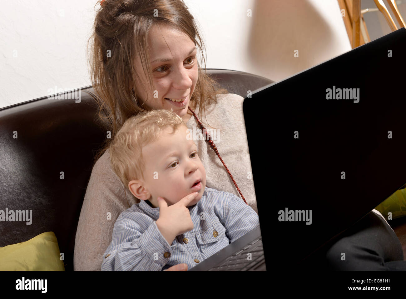 young mother and her child looking at a computer sitting in a brown ...