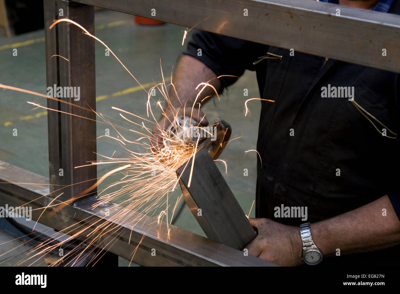Metal Fabrication. A welder grinds the sharp edges of a cut tube prior ...