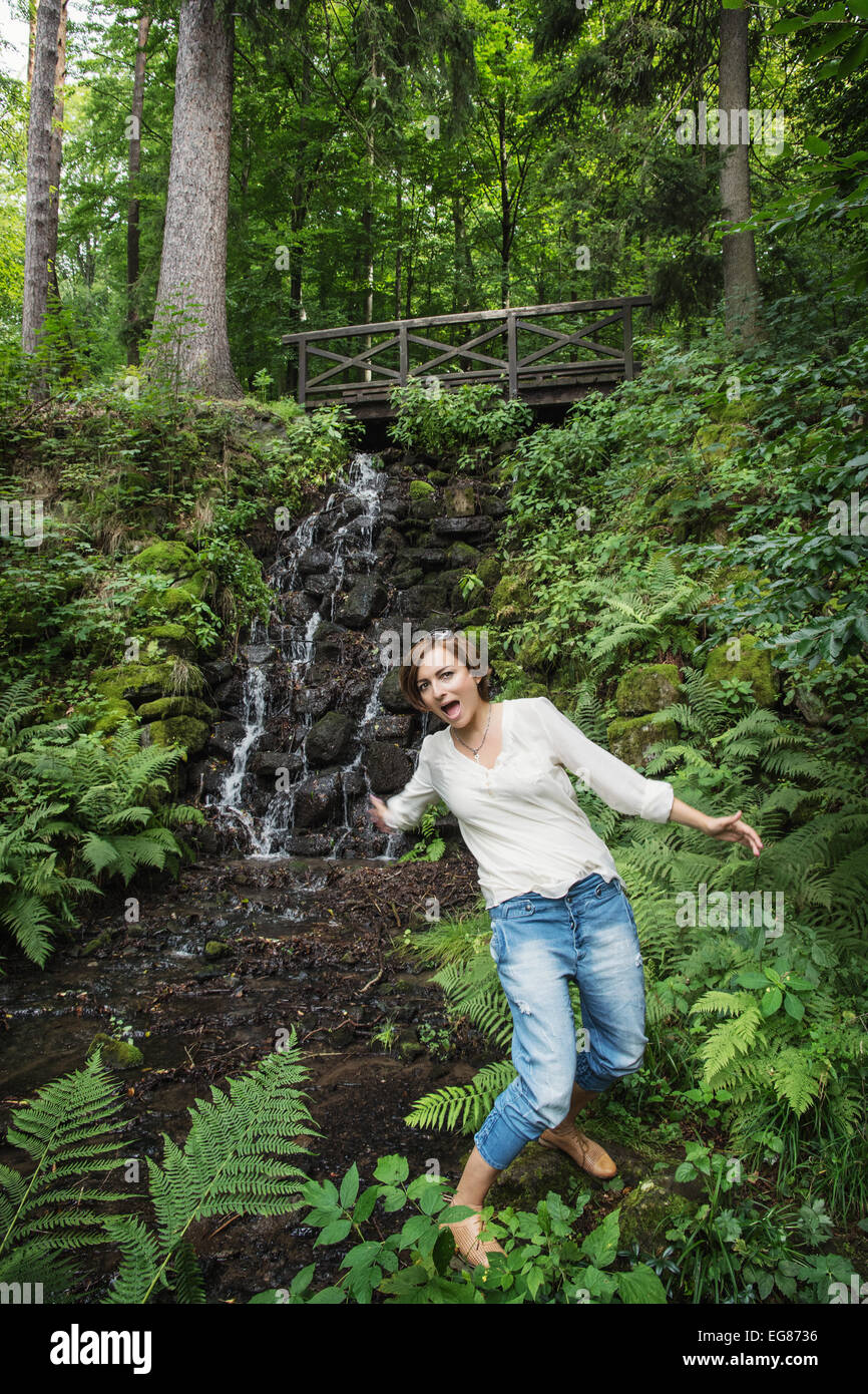 Young woman falls into water. Wooden bridge and waterfall. Hiking theme ...