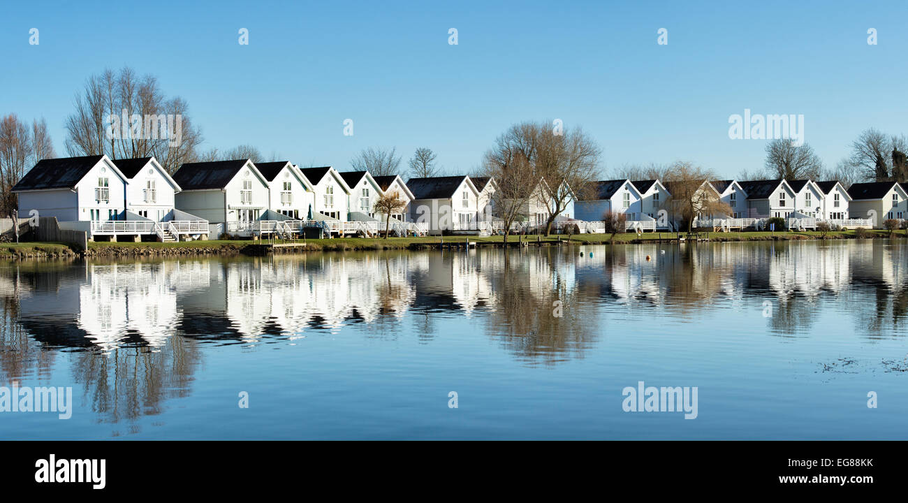 Clapperboard style houses along a lake at the watermark club, Cotswold ...