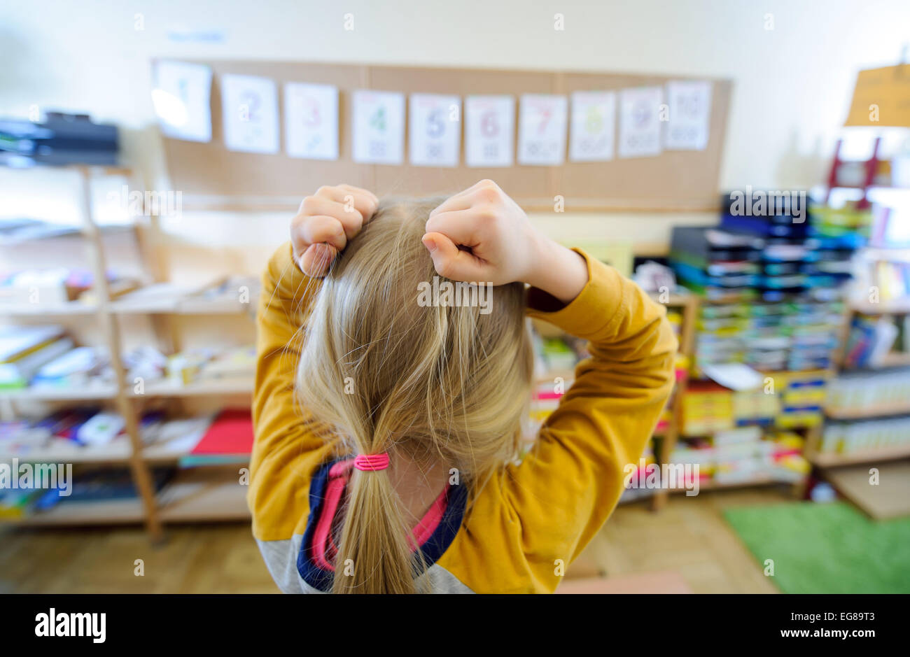 A primary school student pulls her hair as she stands in front of a ...