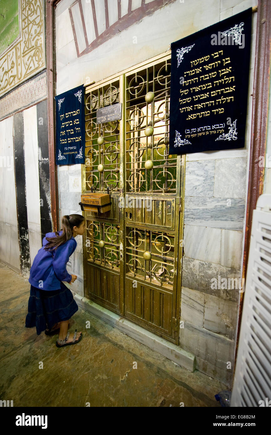 A young girl is watching through the bars of an iron door to the tomb ...