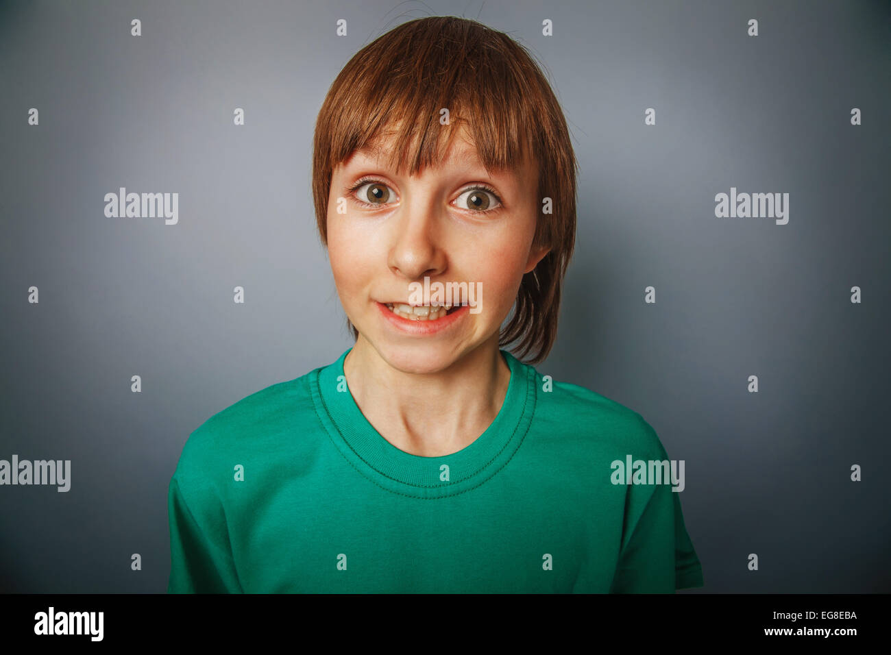 European-looking boy of ten years surprise smile on a gray background ...