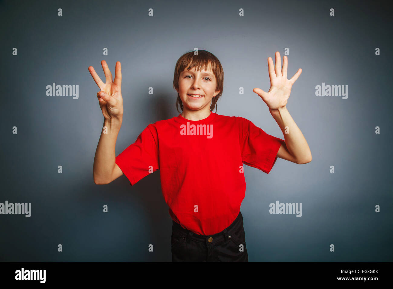 European-looking boy of ten years shows a figure eight finger on a gray ...