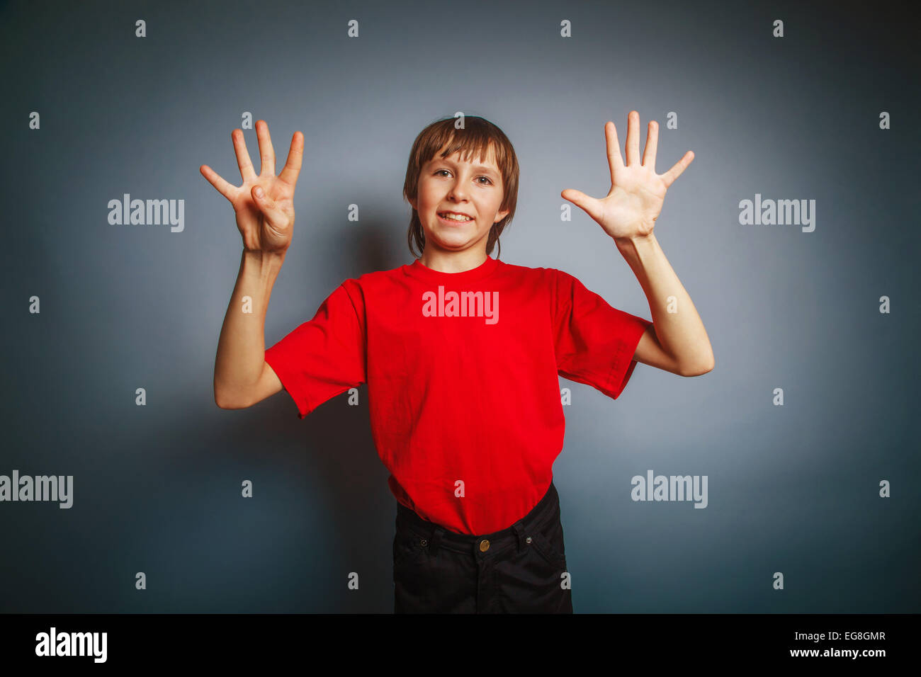 European-looking boy of ten years shows nine digit finger on a gray ...