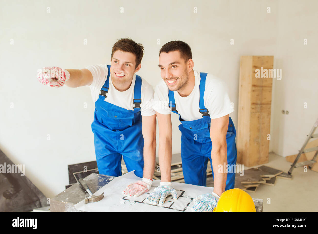 smiling builders with blueprint Stock Photo - Alamy
