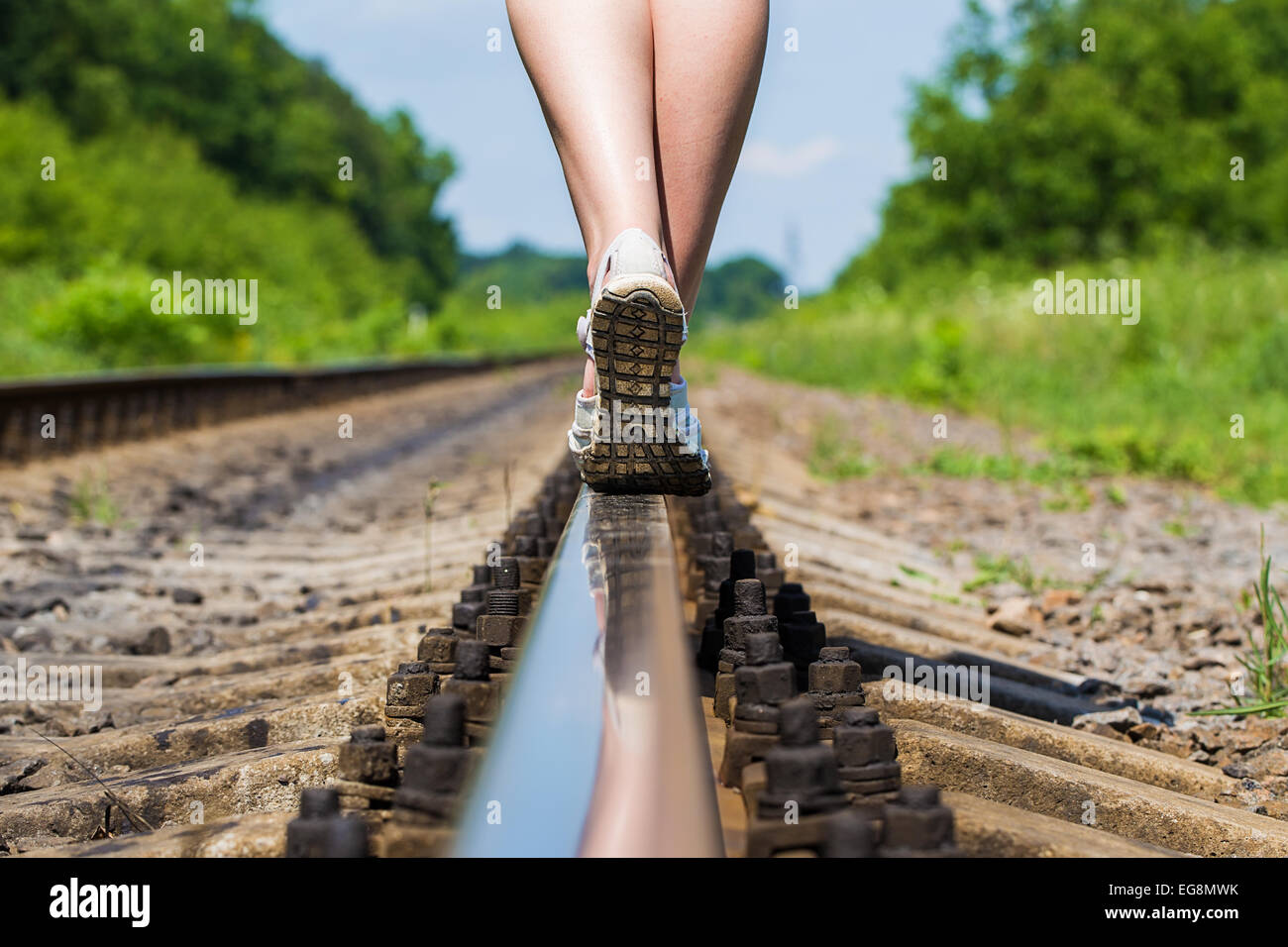 female legs in sneakers on the rail of the railway Stock Photo - Alamy