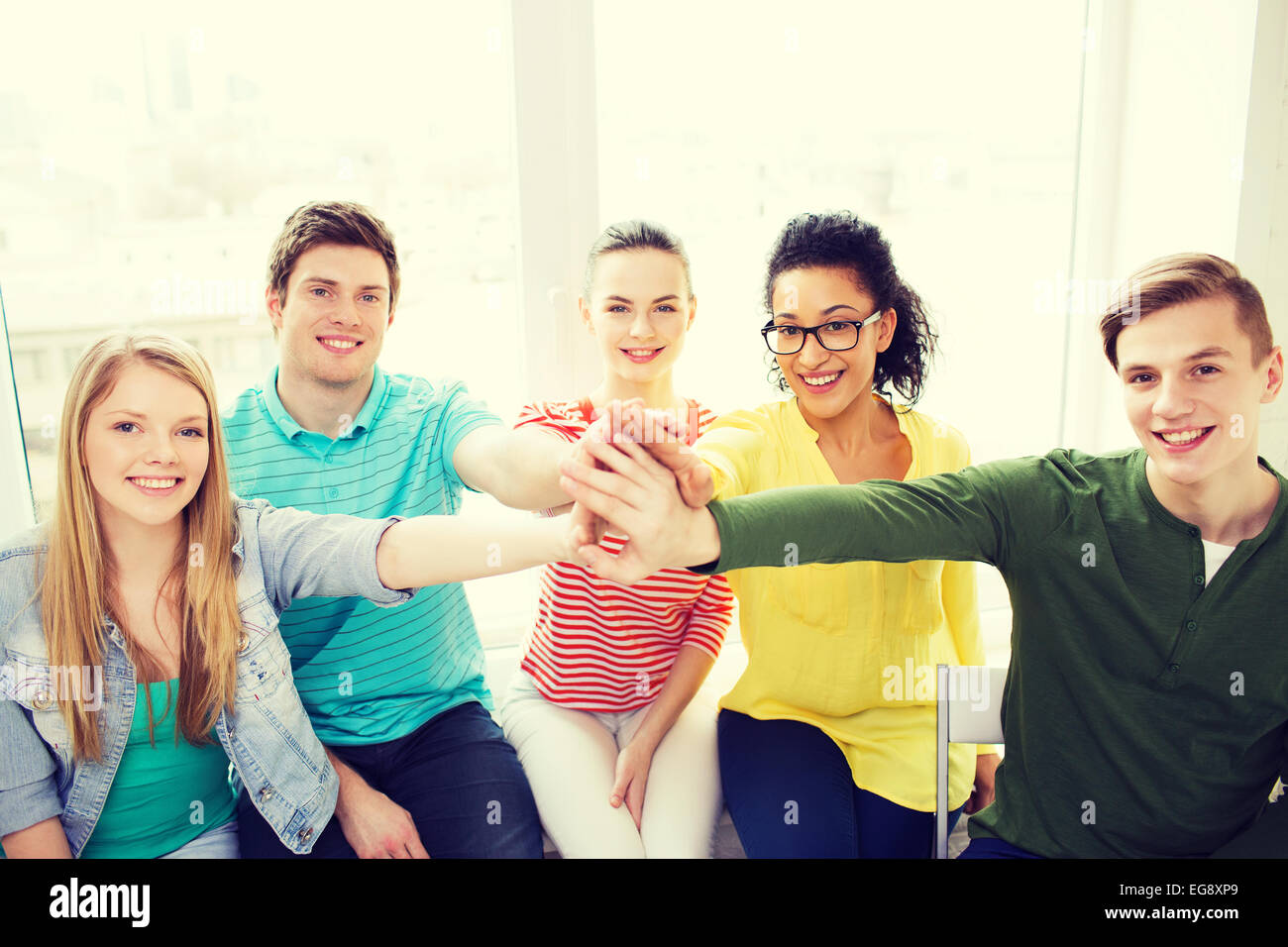 smiling students making high five gesture sitting Stock Photo - Alamy