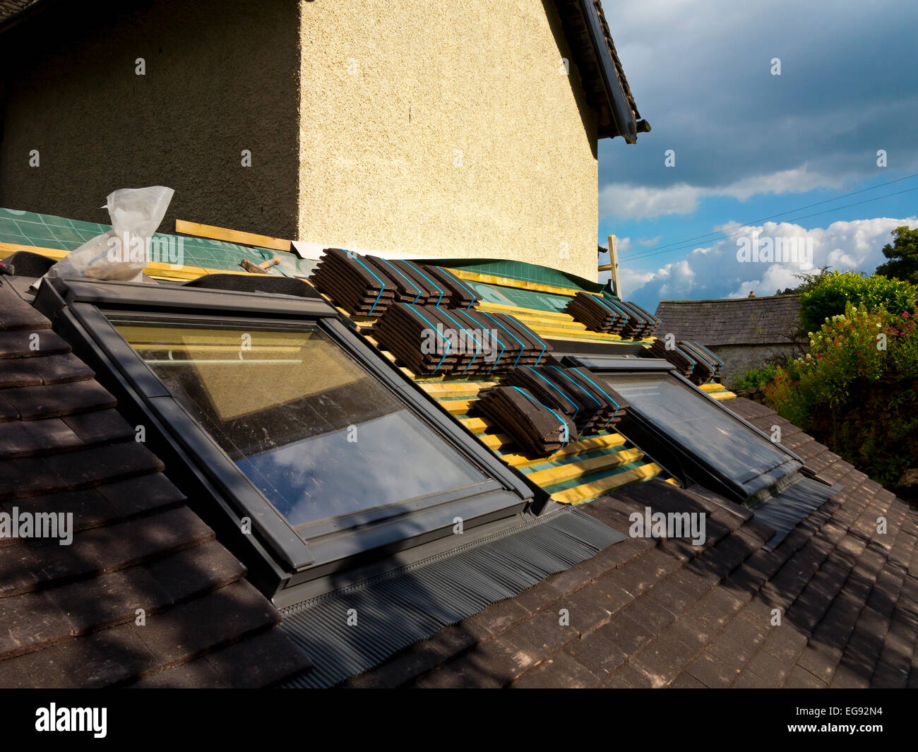 Roof repairs on a house with new tiles ready to be installed around two ...