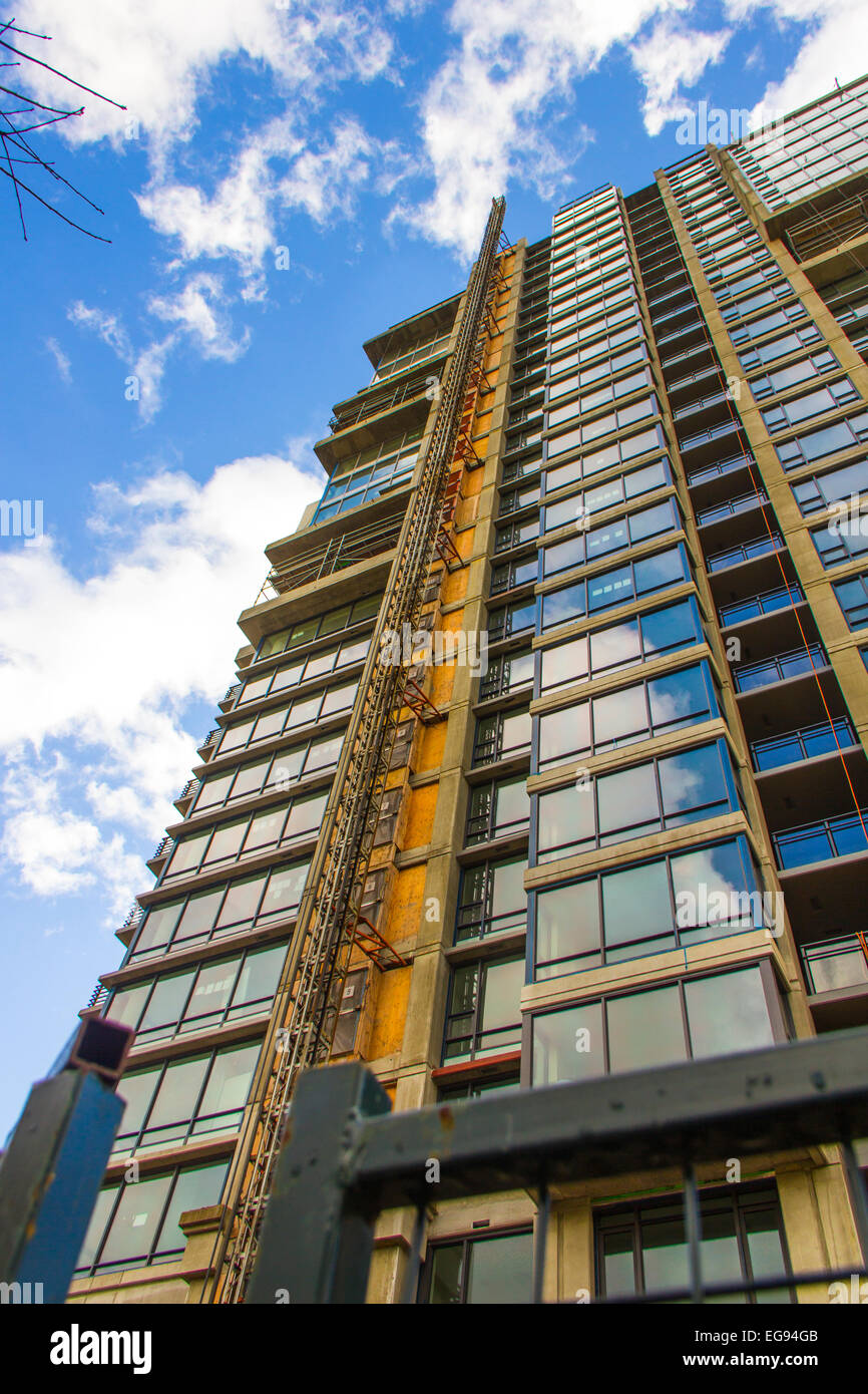 Shiny new condominium tower under construction with blue sky and clouds ...