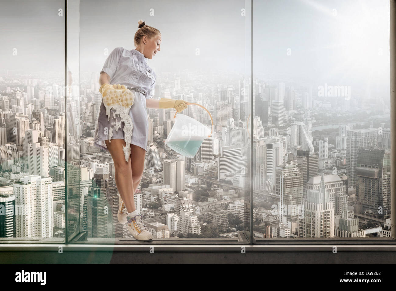 portrait of young hotel maid washing glass on the big city background ...