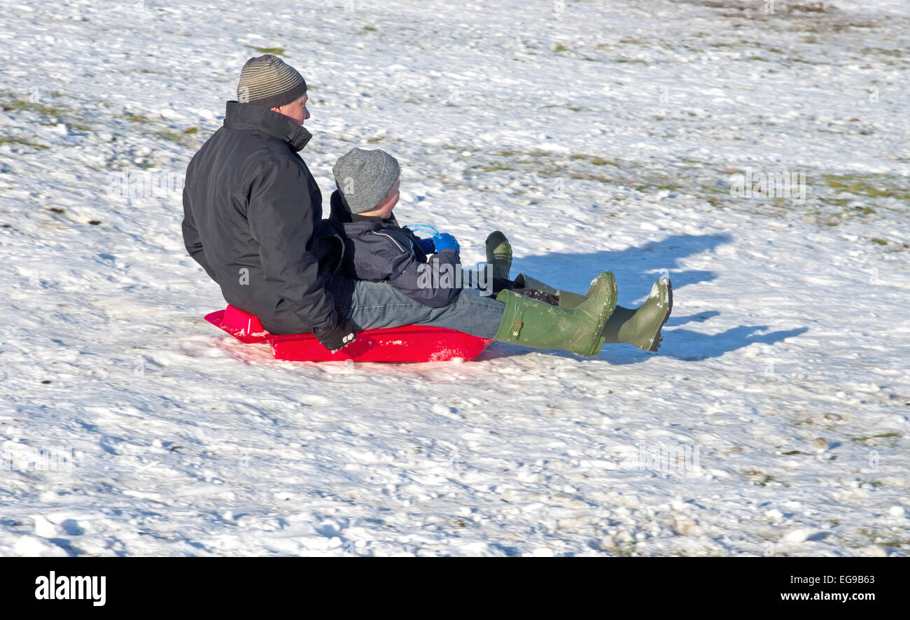Man and boy on sledge together sledging downhill on snowy hillside ...