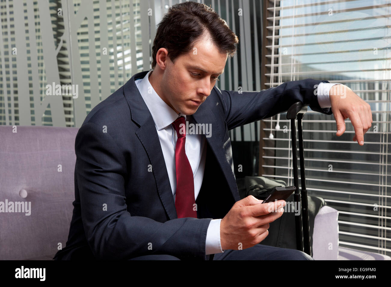 Businessman at airport lounge, checking phone Stock Photo - Alamy