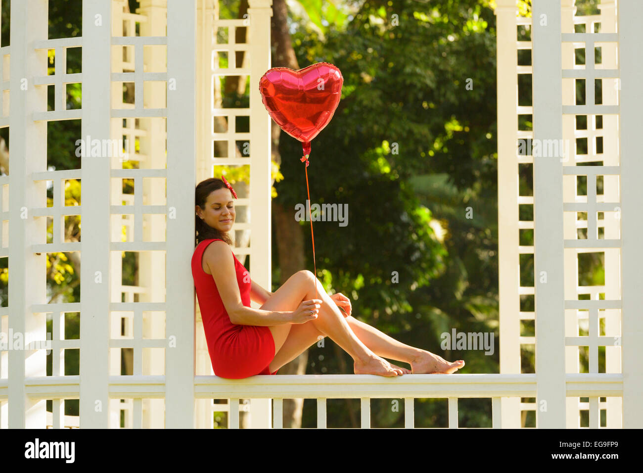 Woman with red heart shape balloon sitting on park bench Stock Photo ...