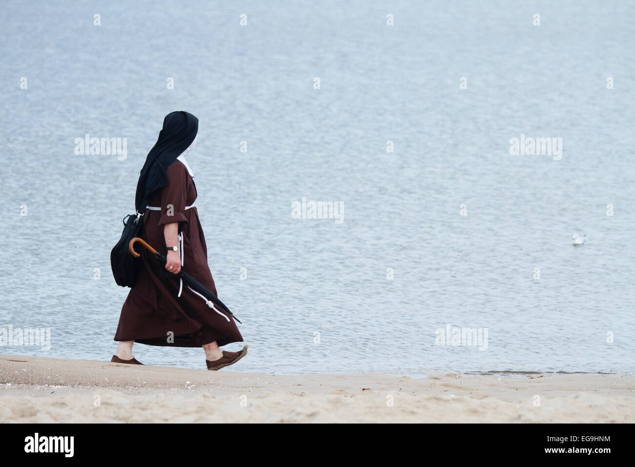 A nun walking alone on the bech Stock Photo - Alamy