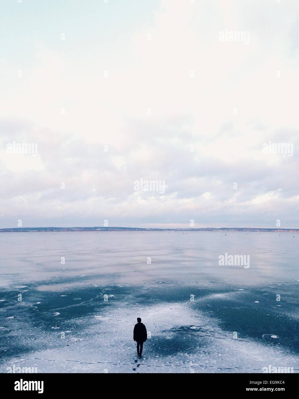 Man walking away across frozen lake Stock Photo - Alamy