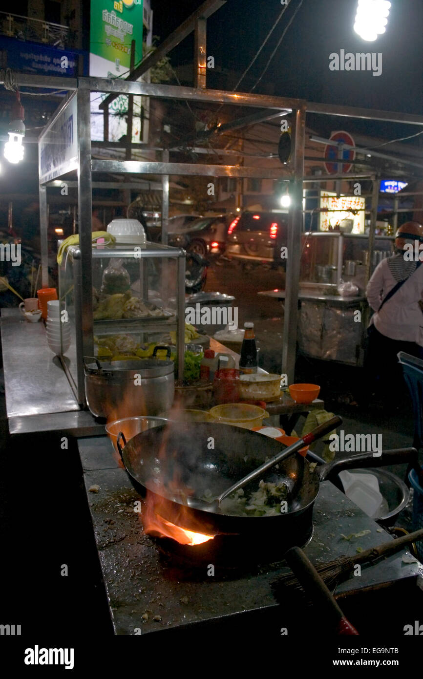 Street food is frying in a pan on a mobile food cart on a city street ...