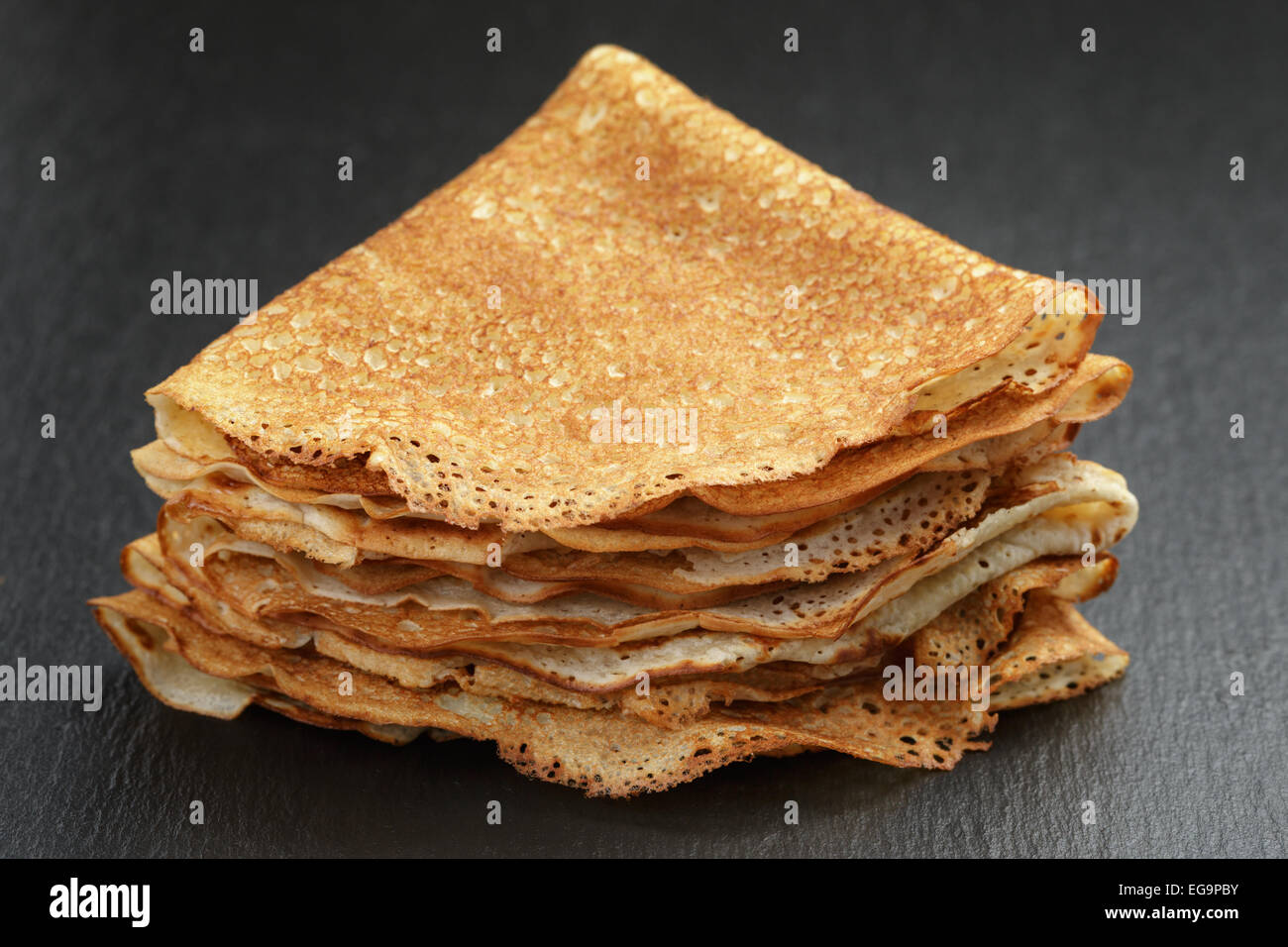thin crepes or blinis folded in triangles on slate board Stock Photo ...