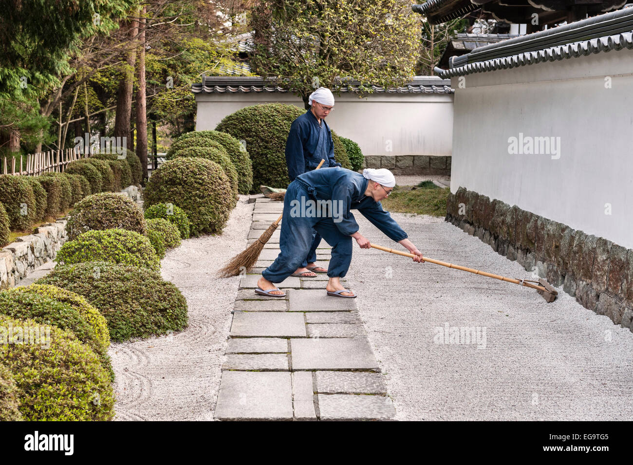 Young Zen Buddhist monks sweeping paths and raking the gravel early in ...