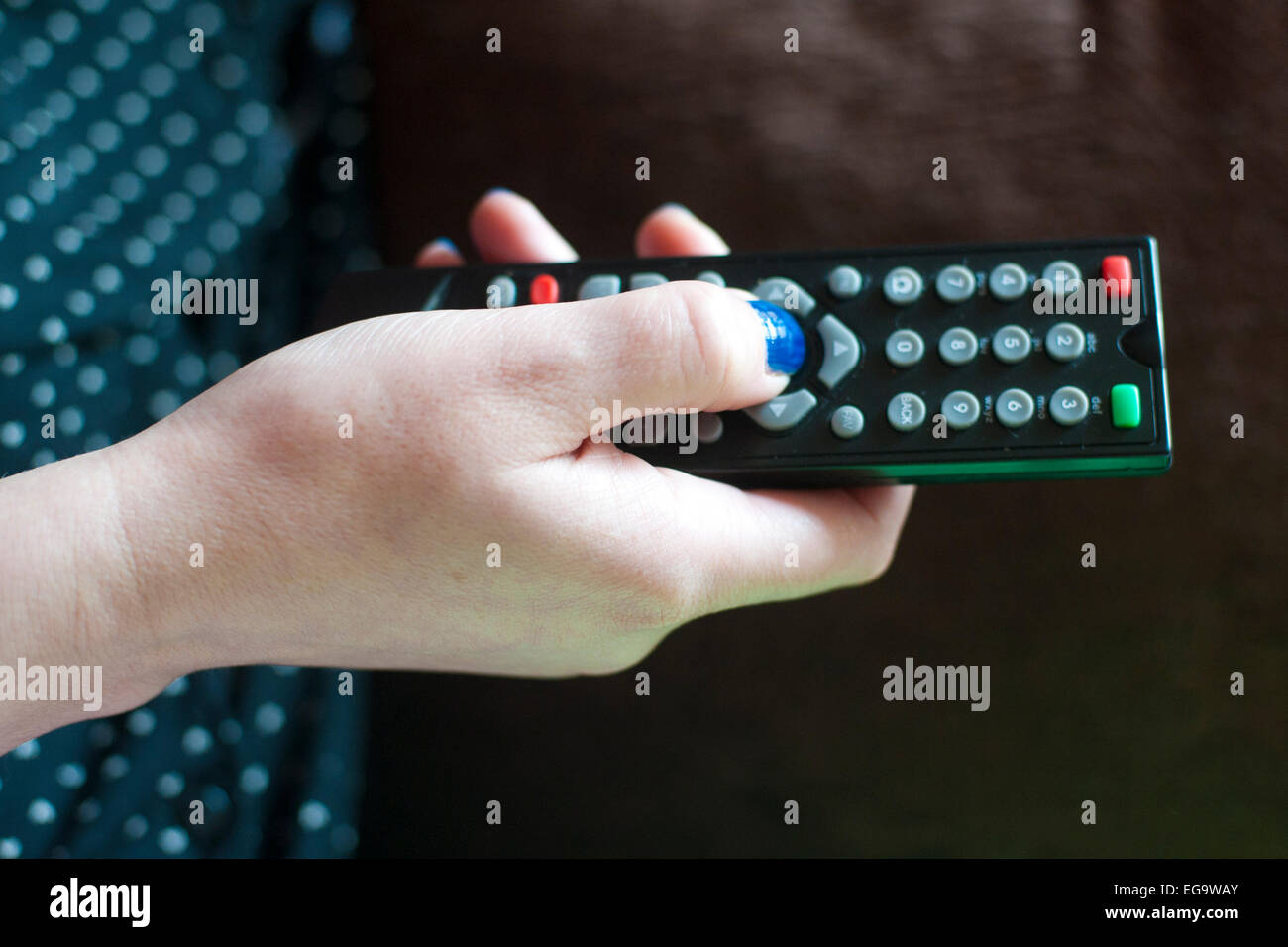 a woman changes the tv channel with a remote control in her hand Stock ...