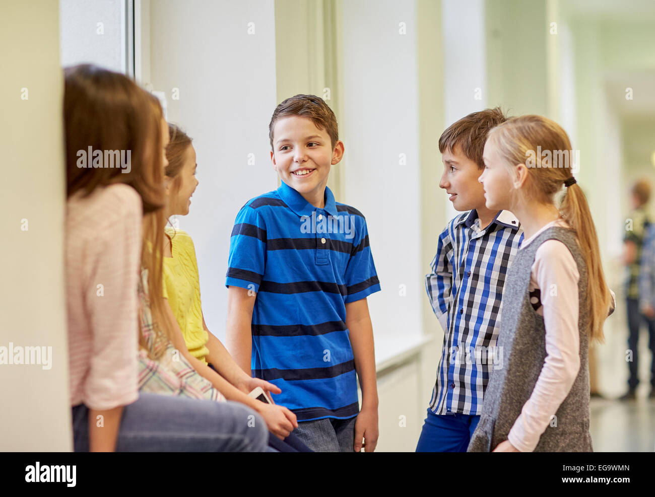 group of smiling school kids talking in corridor Stock Photo - Alamy